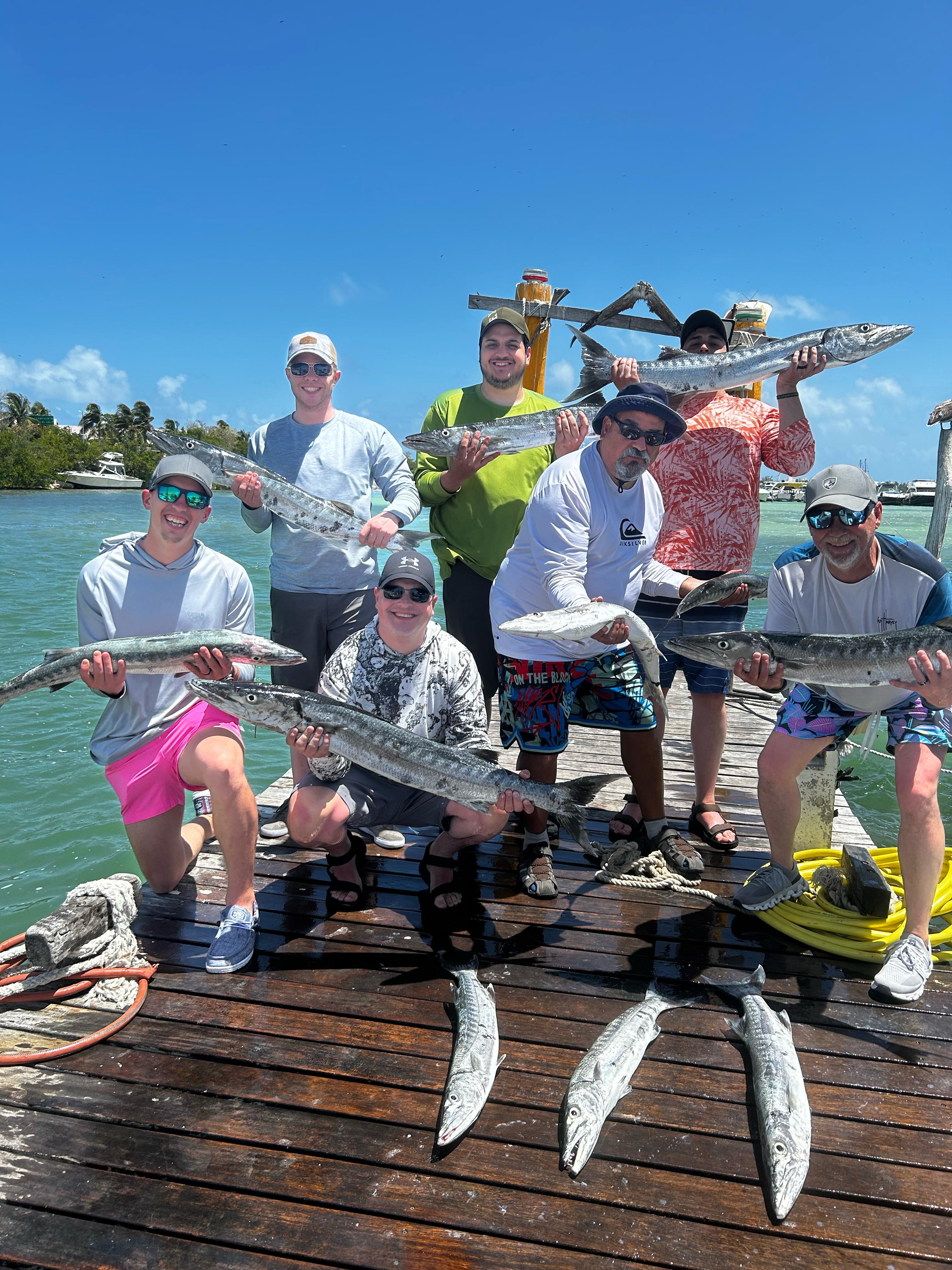 Friends displaying a big barracuda haul at the dock after a successful ...